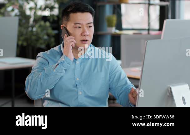 In a bright, modern office, a professional man speaks on the phone ...