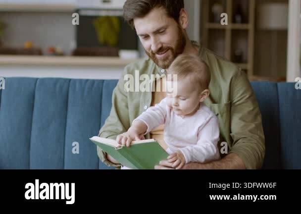A joyful father shares quality time with his baby on a blue couch in a ...