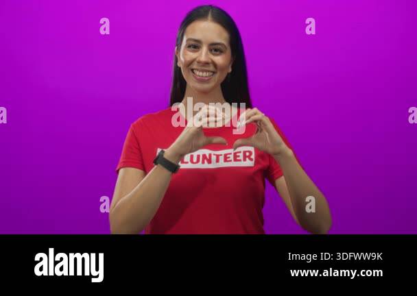 Woman volunteer forming heart with hands and smiling in studio against ...