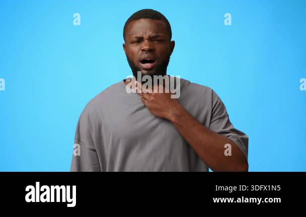 A young African American man stands against a solid blue background ...