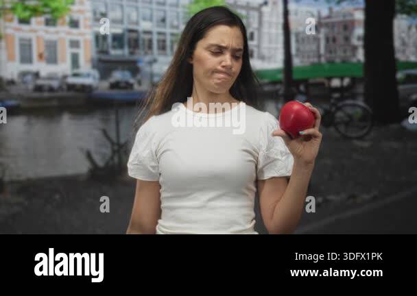 Woman holds apple on a canal street in amsterdam with a displeased ...