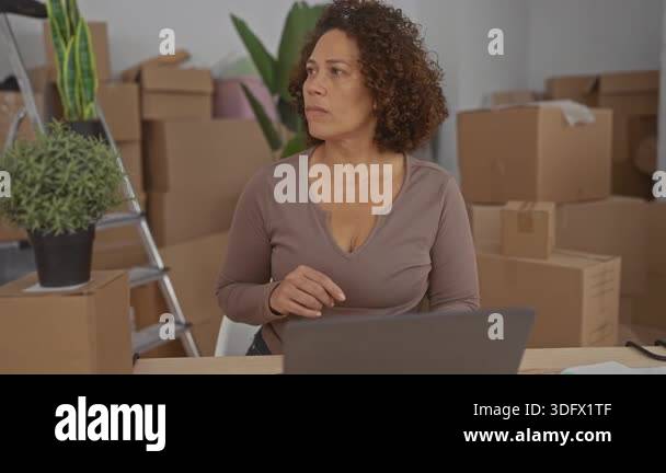 Woman points finger at stacked cardboard boxes and green potted plant ...