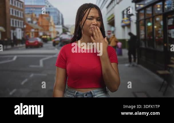 Woman hand covering mouth on city street wearing red crop top and denim ...