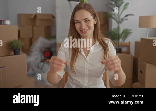 Woman smiling warmly makes heart shape with hands in new building ...