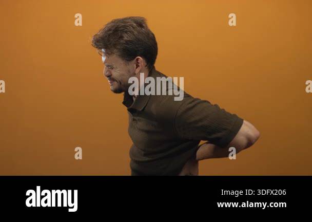 Young hispanic man with hand on lower back, wincing and hunched over in ...