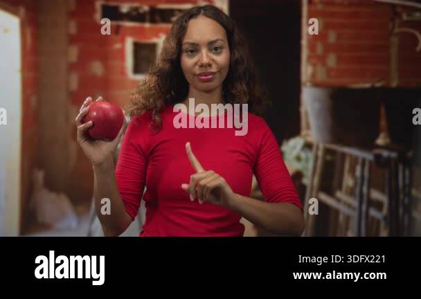 Woman holding apple and points finger in building interior, hand ...