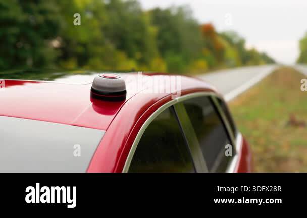 Beacon V16 amber emergency light on a red car parked roadside, with a ...