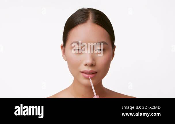 A beautiful young woman is pampering herself with skin care, applying ...