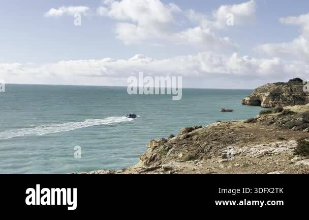 Aerial view of Benagil Cave from the sea with a large group of kayakers ...