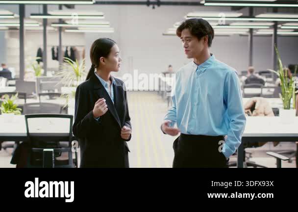 Two young Asian professionals converse in a contemporary office ...