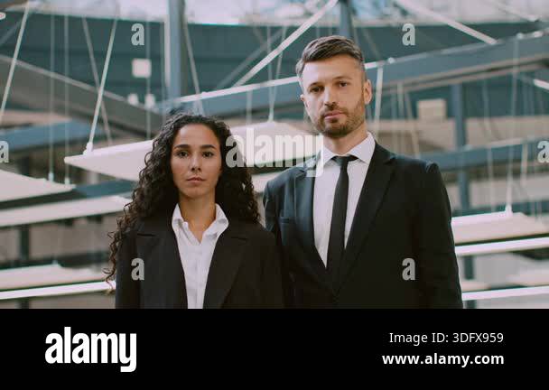 Two business professionals, a man and a woman, stand together in a ...