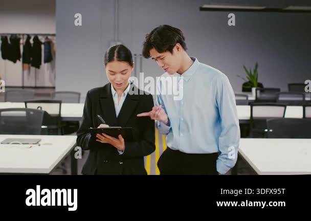 In a contemporary office setting, a young Asian woman writes on a ...