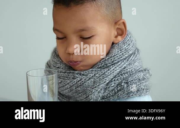 In a cozy setting, a young African American boy sits quietly wrapped in ...