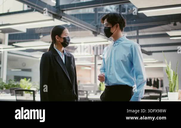 Two young Asian professionals are discussing ideas in a spacious ...