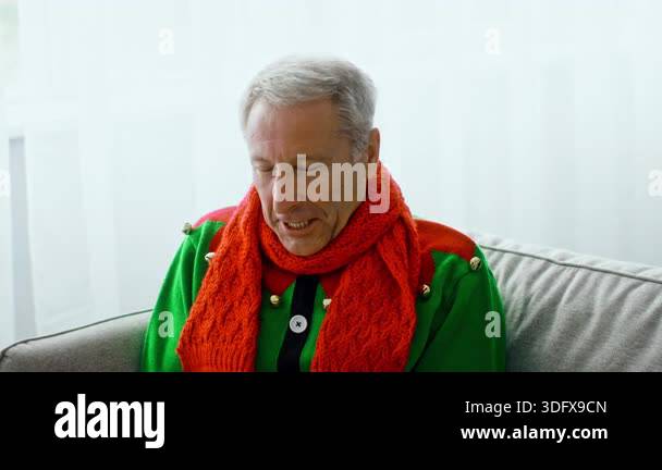 An elderly man in his 60s relaxes on a comfortable couch while wearing ...