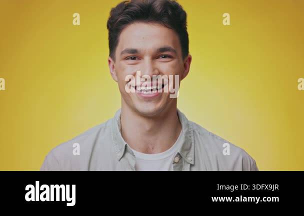 A young, handsome man joyfully smiles at the camera against a vibrant ...