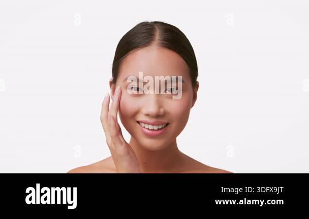 A beautiful young woman with smooth skin is pampering herself ...