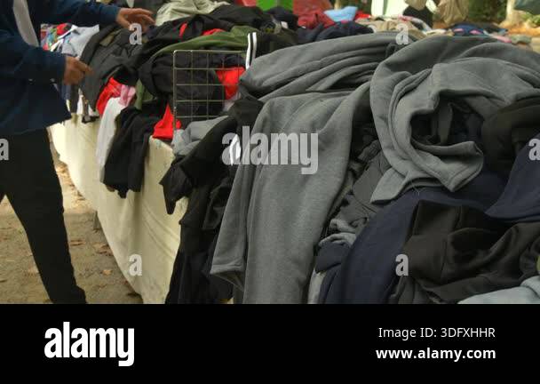 Close-up of a man choosing clothes at an outdoor flea market. Concept ...