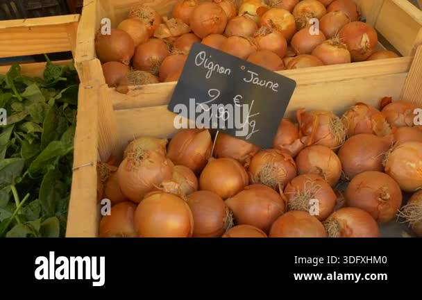 Fresh yellow onions displayed in a wooden crate at a Provencal farmers ...