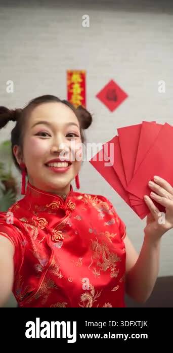 Happy young Asian woman in red cheongsam holding lucky red envelopes ...
