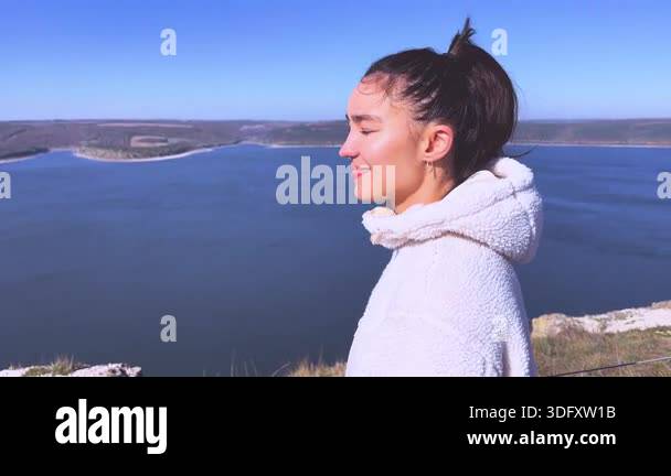 A beautiful young girl looks into the distance enjoying the gorgeous ...