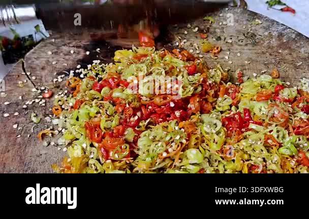Chopped fresh chili peppers on a rustic wooden cutting board with chef ...