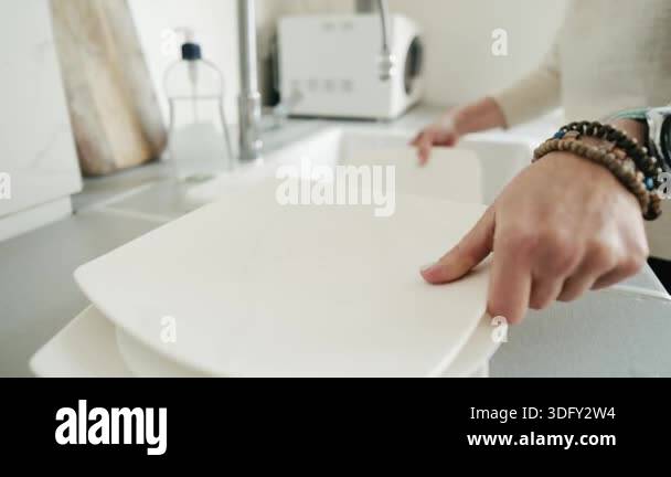 Girl Washing White Plates In The Kitchen Sink And Stacking The Clean ...