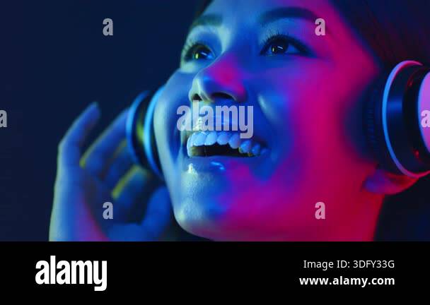 A young Asian woman smiles with joy as she listens to music through ...