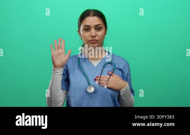Young hispanic female nurse makes an oath gesture with her hand on ...