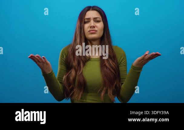 Woman expressing frustration with closed eyes against a vibrant blue ...
