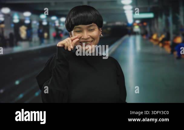 Chinese woman in black gestures small size in a modern indoor train ...