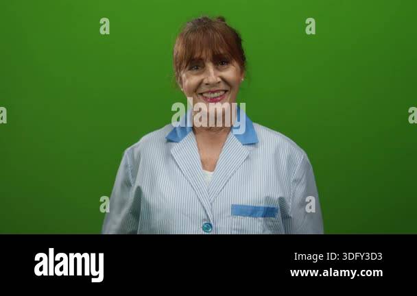 Senior hispanic woman in cleaning uniform smiling against vibrant green ...