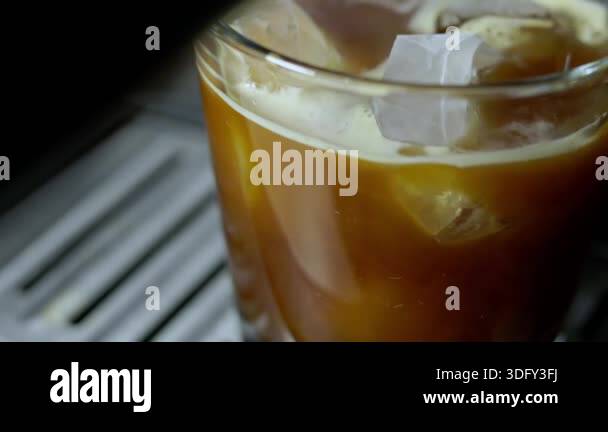 Slow motion of coffee pouring in glass with ice from machine Stock ...