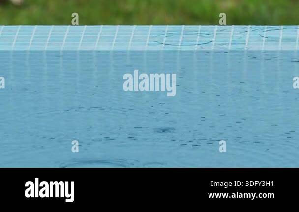 Raindrops falling on the smooth surface of the pool. Slow motion Mid ...