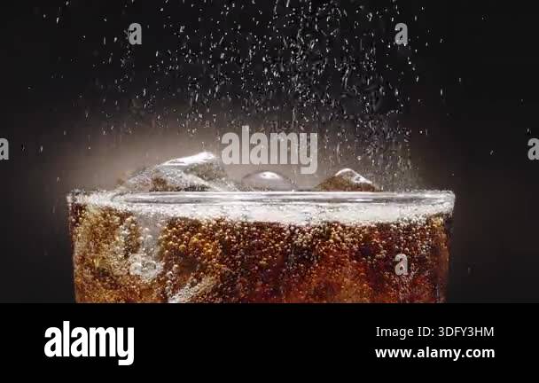 Close-up shot of cola glass top with ice with visible foam, fizz and ...
