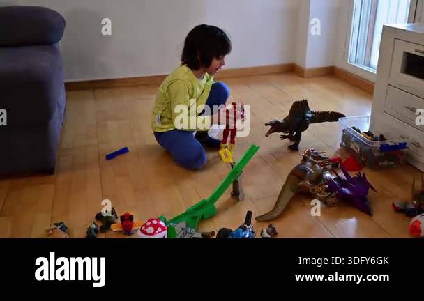 Happy kid enjoying his toys, including cars and dinosaurs, while ...