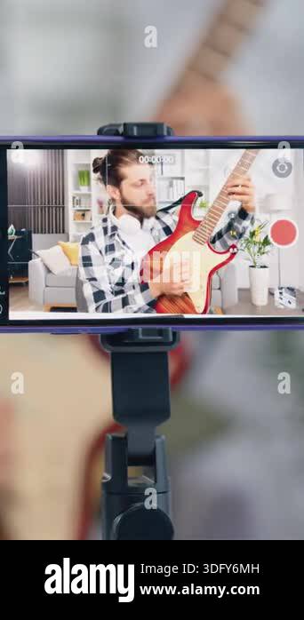 Close up screen smartphone. Young male blogger wear headphones playing ...