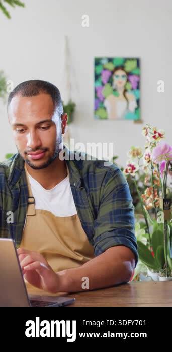 African american couple working in own flower shop. Man typing on ...