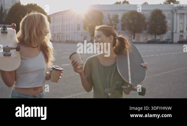 Two skateboarder girls have fun and drink coffee Stock Video Footage ...