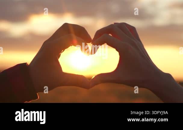 Hands of woman and man made a heart shape at sunset, on the abstract ...