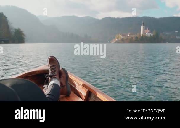 First person view of female feet in brown boots in wooden boat floating ...