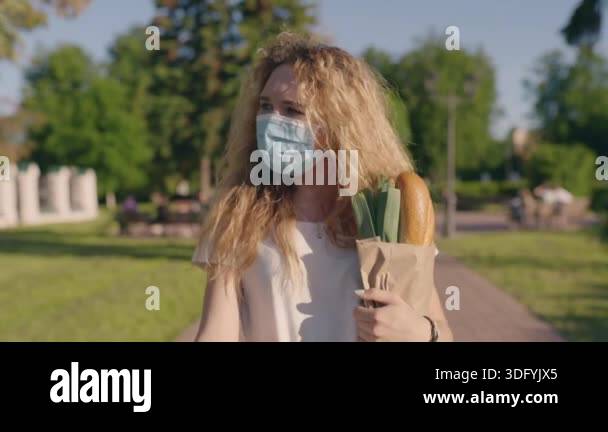 Pandemic shopping. Young woman in protective mask and gloves carries ...