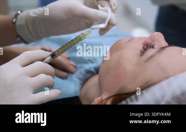 Doctor processes needle and face of girl before procedure. Beautician ...