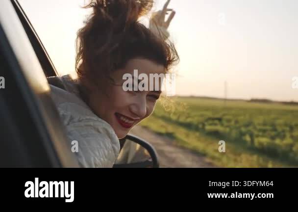 Portrait of young pretty asian girl sitting in car and leaning out of ...