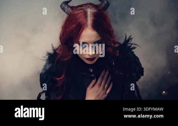 Scary demon doing witchcraft. Red-haired girl witch with black horns ...