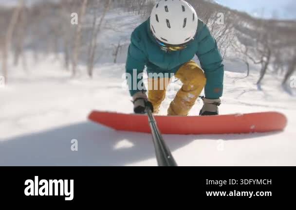 Person filming himself with selfie stick climbing up slope with help of ...