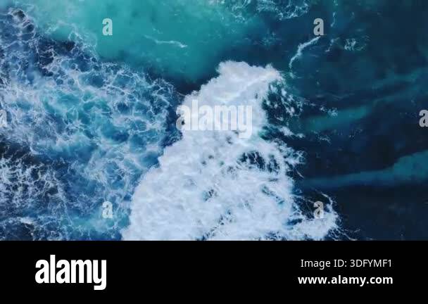 Top down relaxing view of azure water waves meeting with rock cliff ...