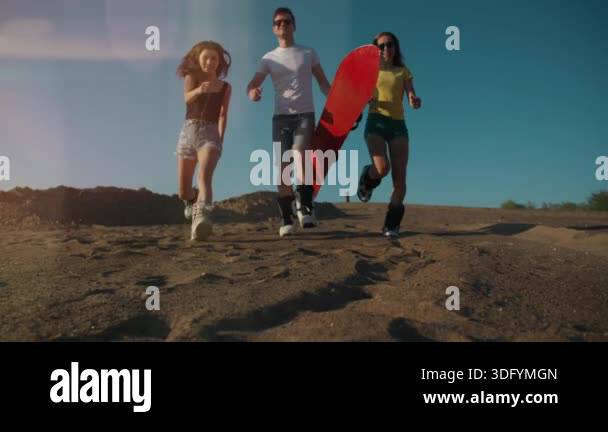 Summer lifestyle. Three young people with red snowboard run and kick ...