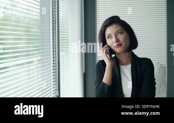 Portrait of young business woman in office talking on phone and smiling ...