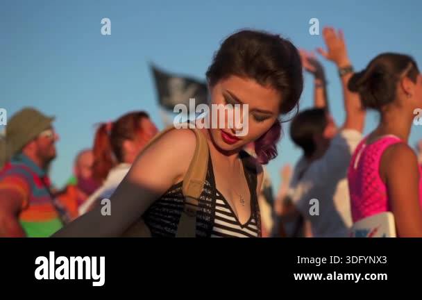 Pretty asian girl dancing at sunset light among the crowd of people at ...